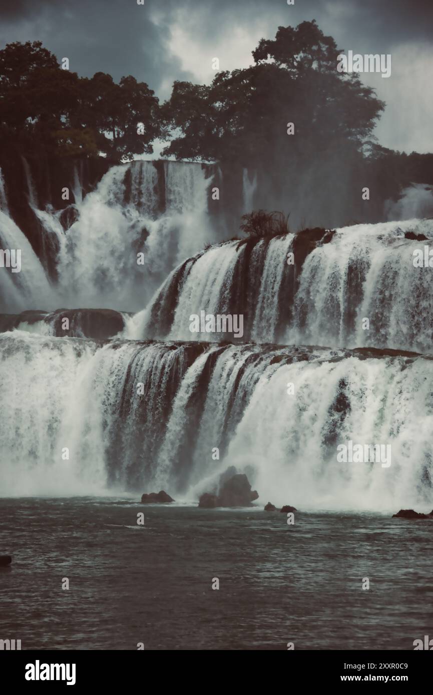 Powerful, cascading waterfalls flow over rugged cliffs, surrounded by ...