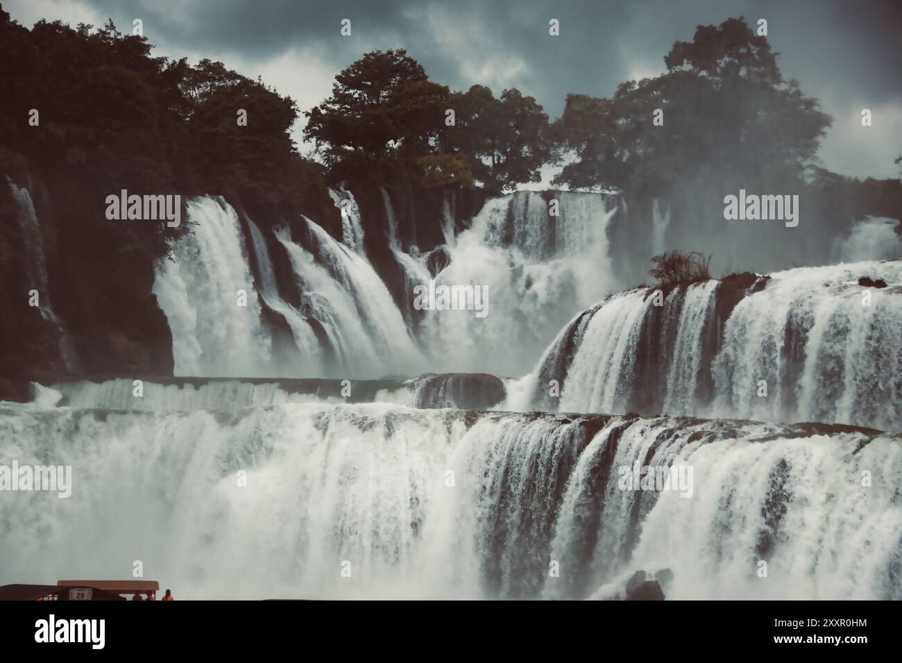 Powerful, cascading waterfalls flow over rugged cliffs, surrounded by ...