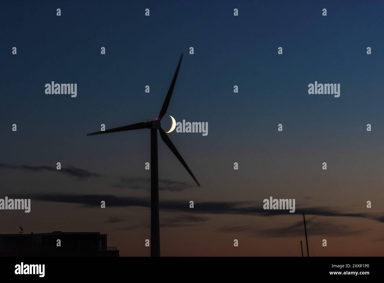 Waxing crescent moon passing behind a wind turbine at night Stock Photo ...