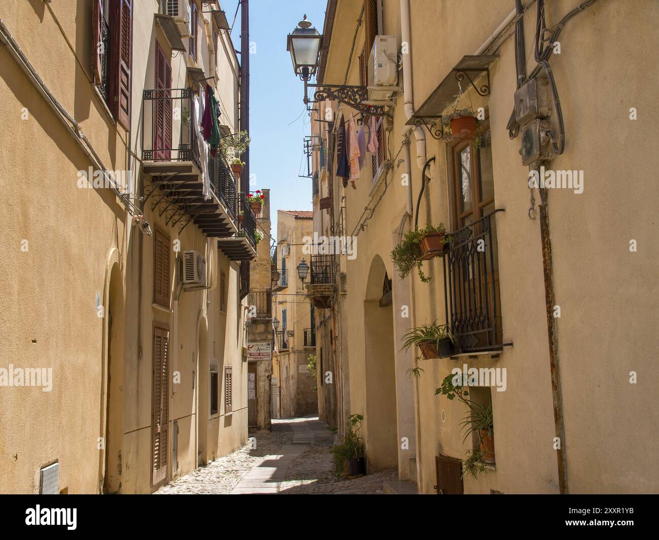 Narrow alley with houses and balconies decorated with flowers ...