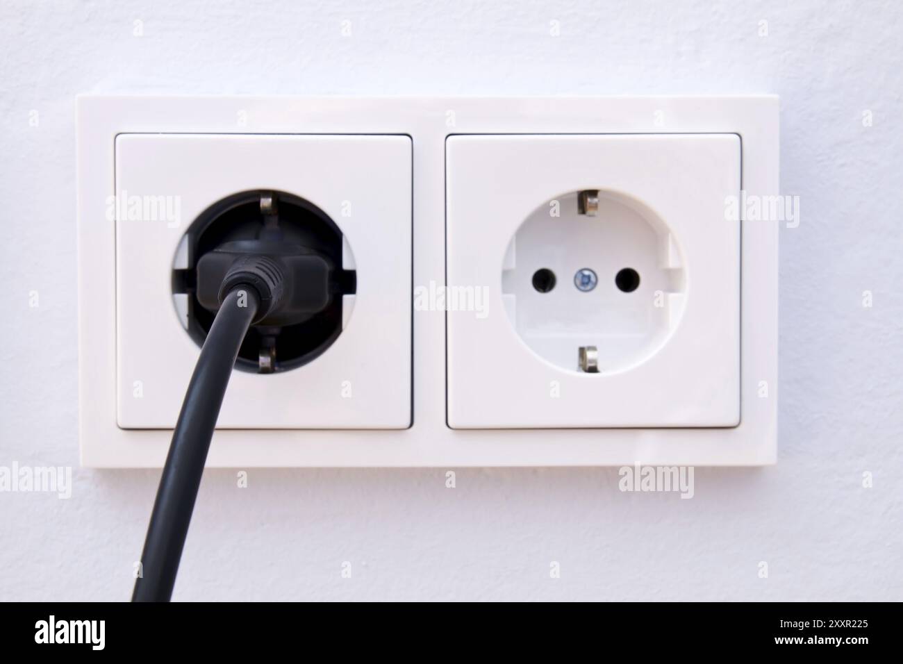 Double socket outlet with plug on white wall Stock Photo - Alamy