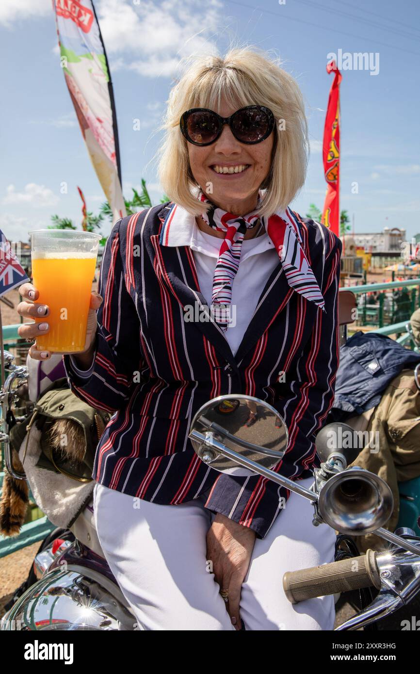 A female Mod wearing a striped jacket holding a glass of orange juice ...