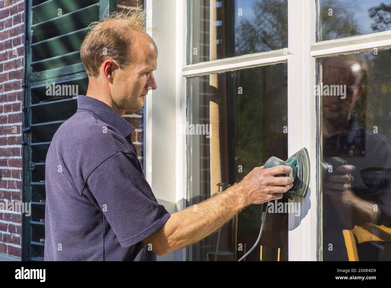 Caucasian painter sanding window frame with electric sander Stock Photo ...