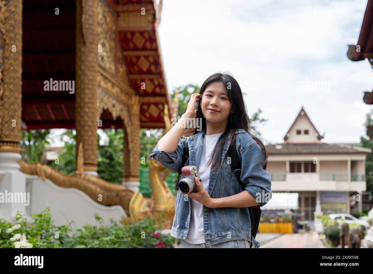 A beautiful, positive Asian female tourist in a denim jacket and ...