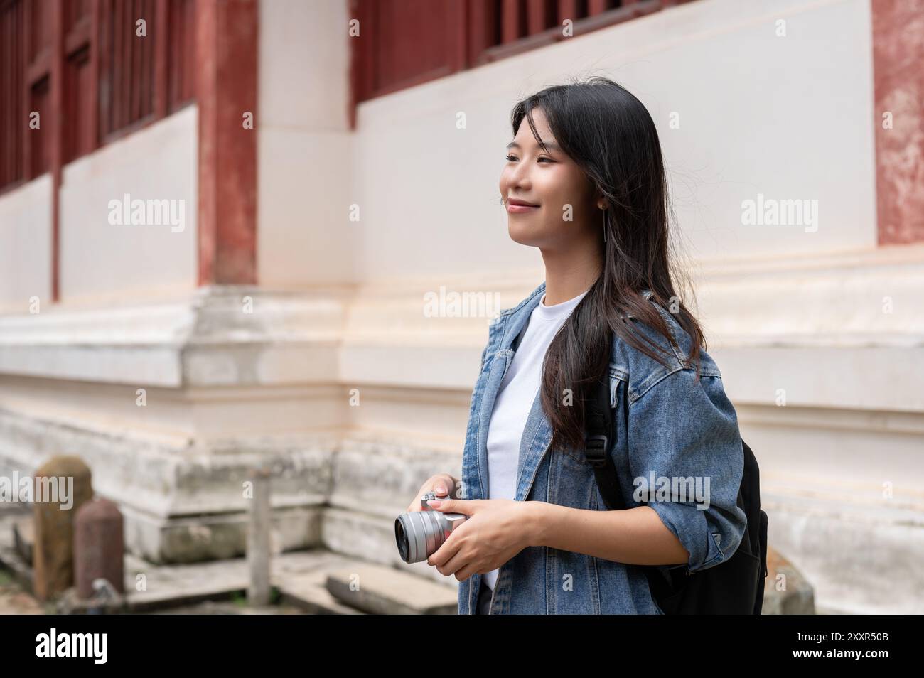 A beautiful, smiling Asian female tourist in a denim jacket and ...