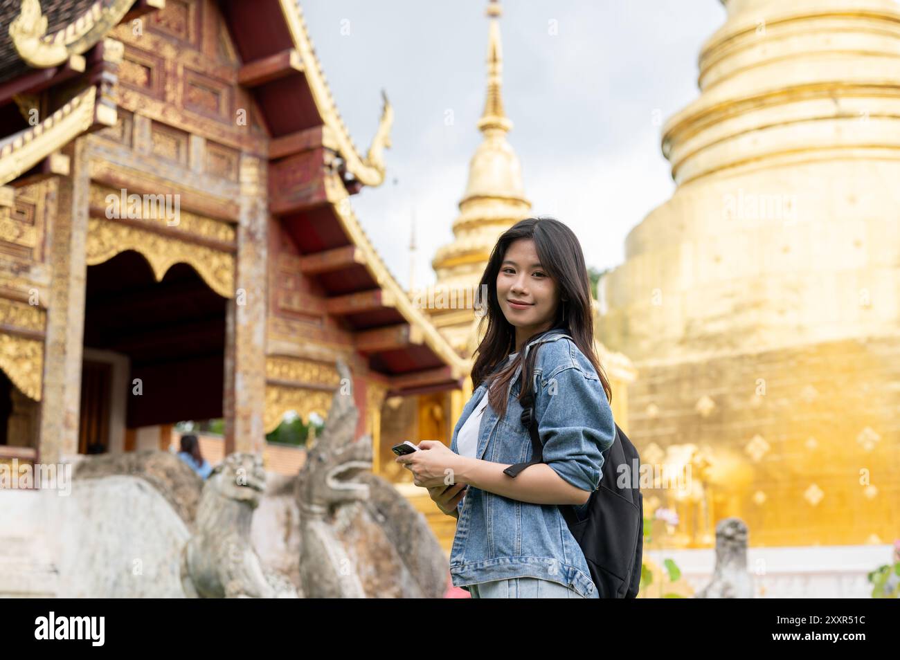 A beautiful, positive Asian female tourist in a denim jacket and ...
