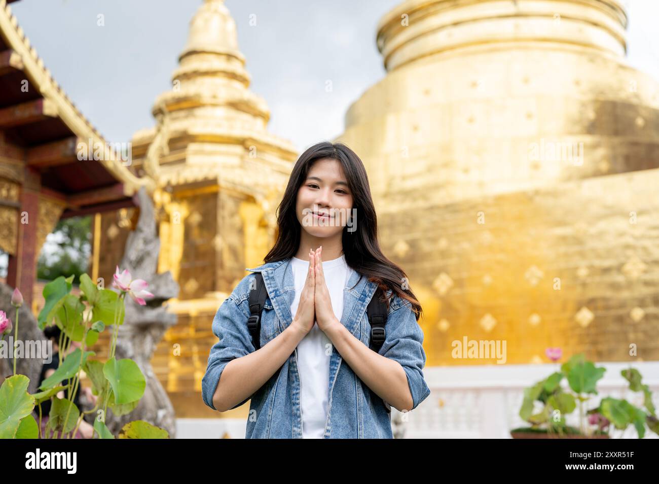An attractive, beautiful young Asian female tourist in a denim jacket ...