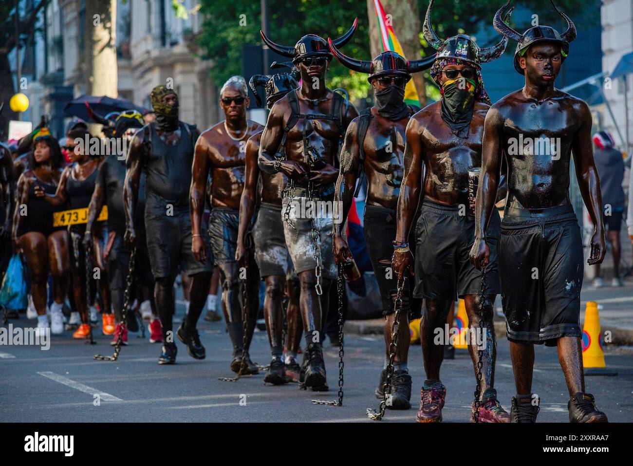 Jab Jab (devil) people walk in line with their chains. The character is ...