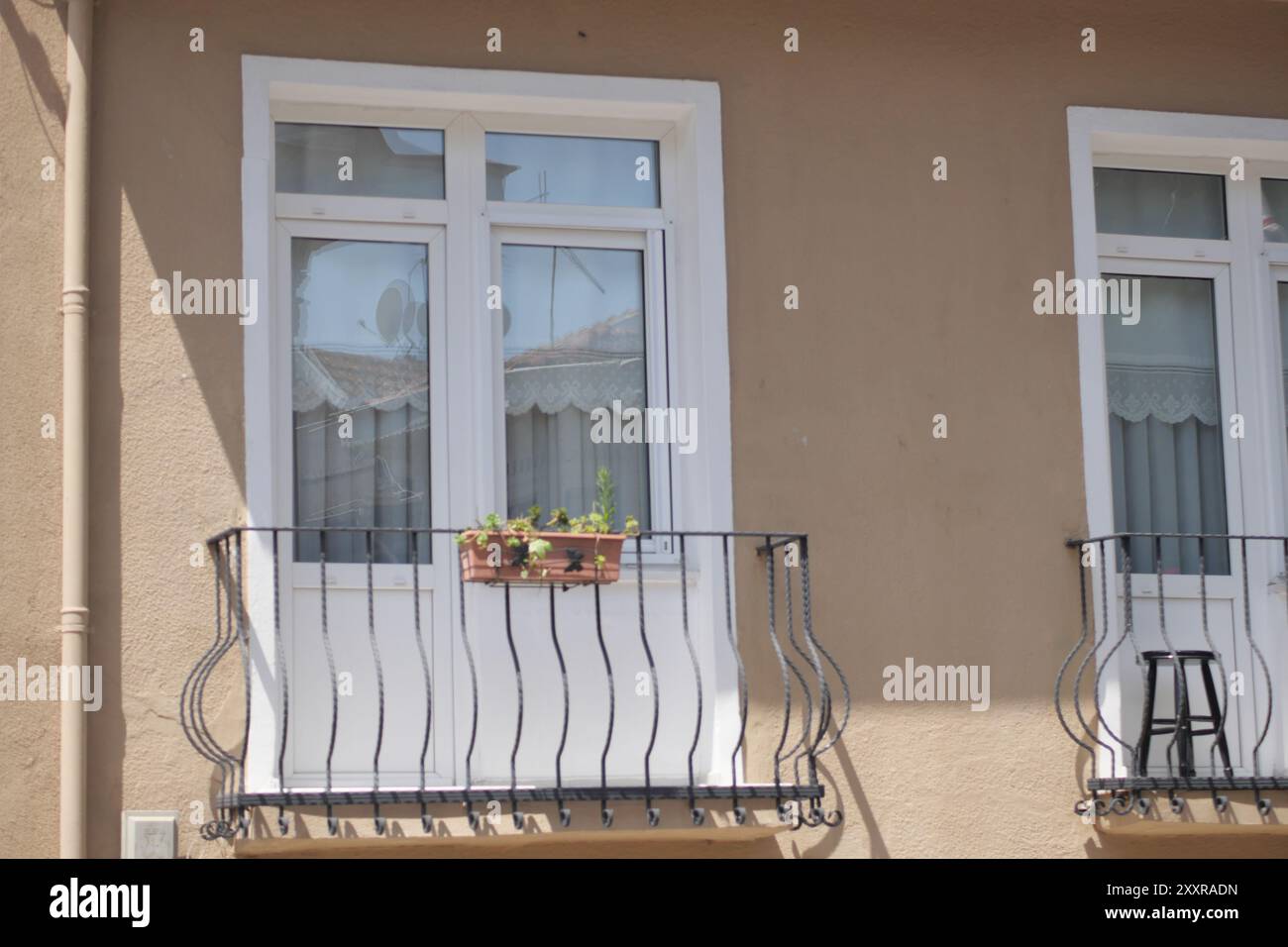 A charming balcony with a flower pot and elegant white French windows ...
