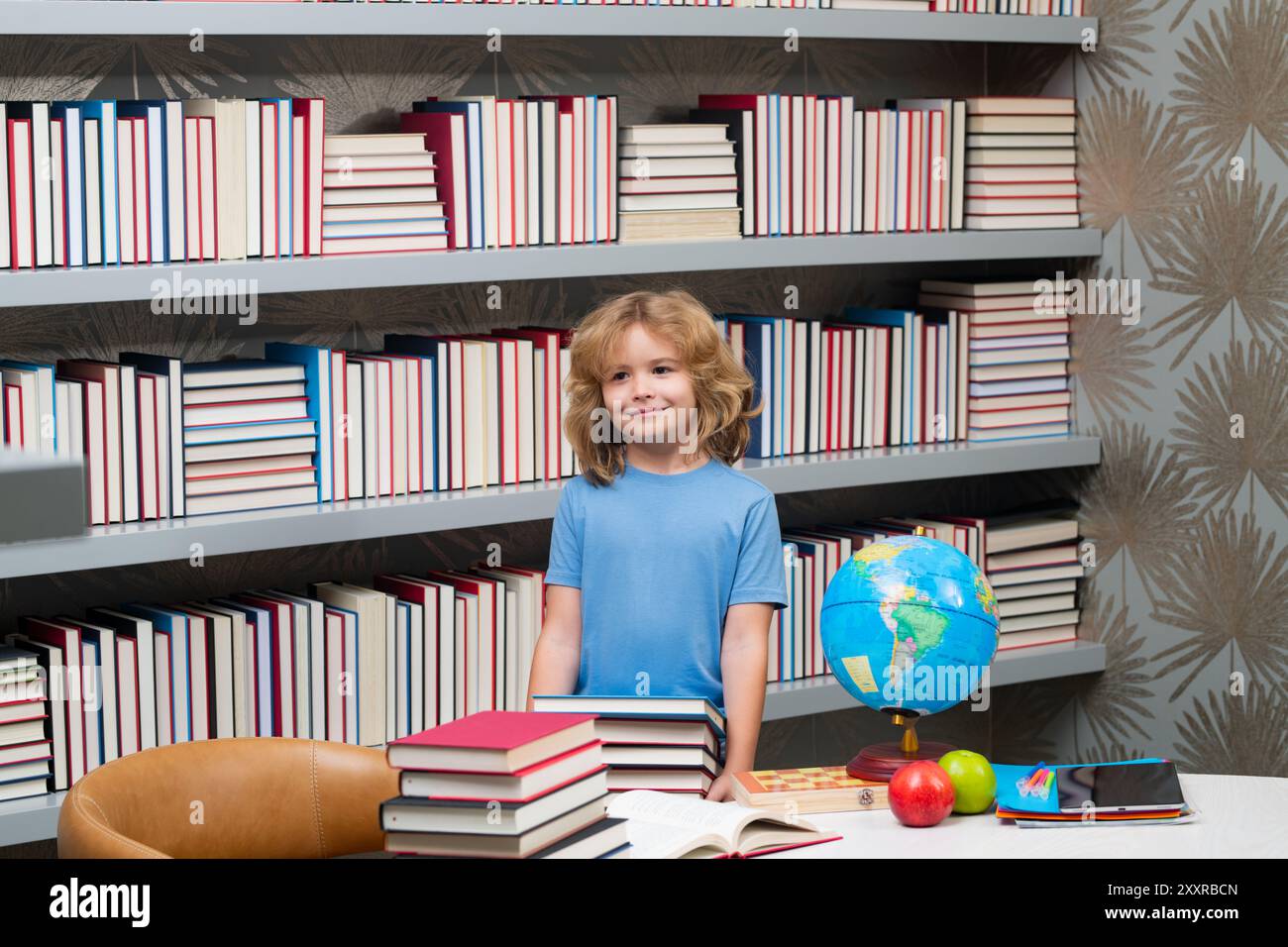 School boy with stack of books in library. School and kids. Cute blonde ...