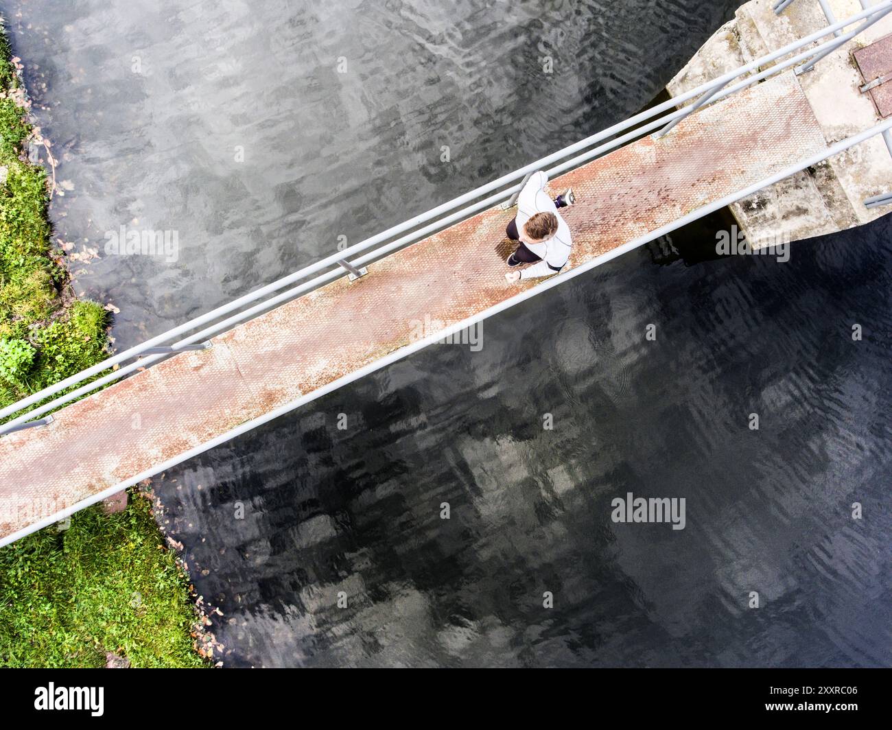 Aerial view of a runner running across bridge in park on a jogging path ...