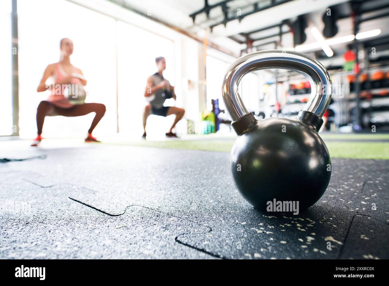 Kettlebell on floor in gym, people doing kettlebell swing behind. Gym ...
