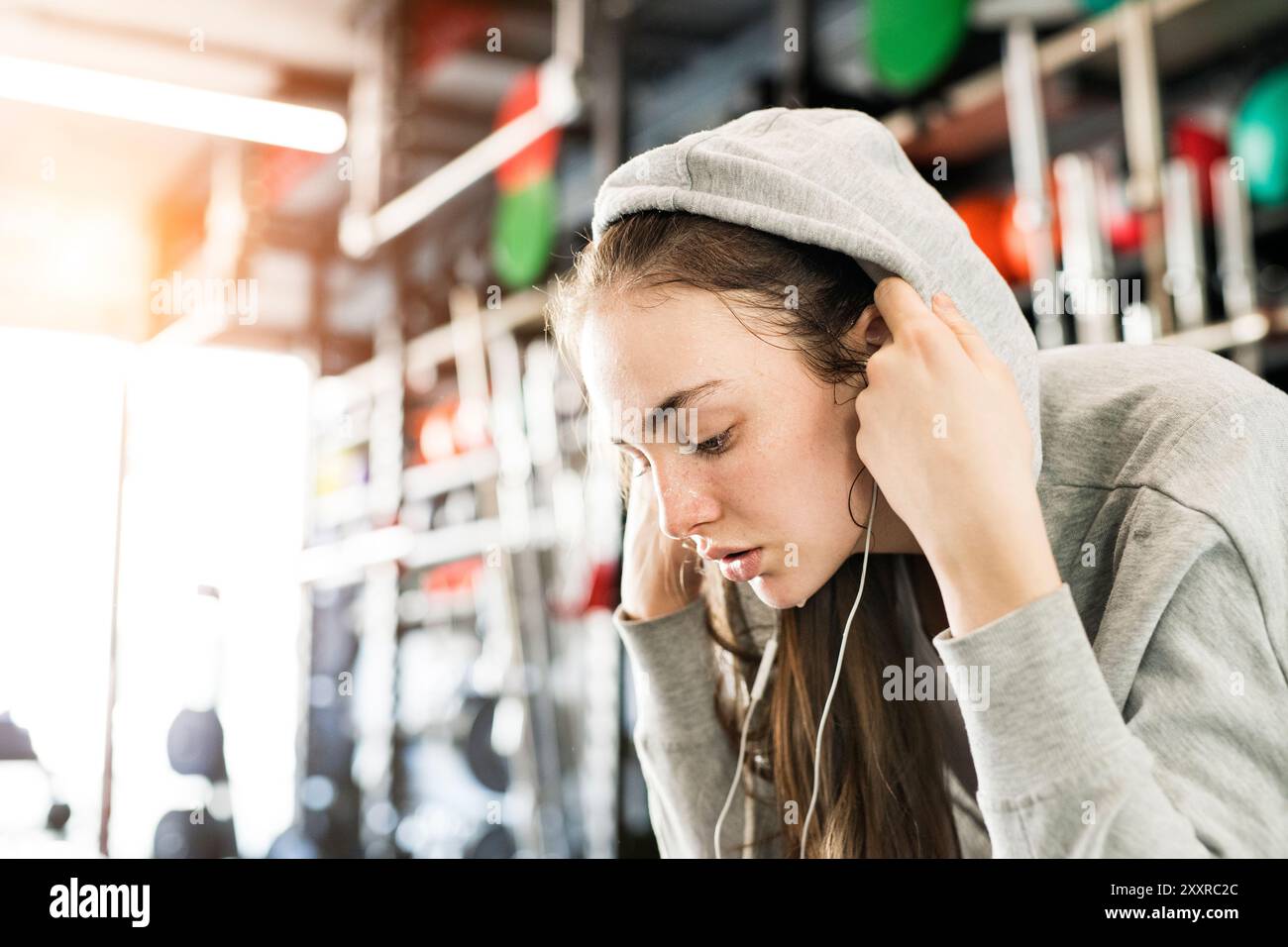 Young fitness girl feeling exhausted after hard workout in gym, sitting ...