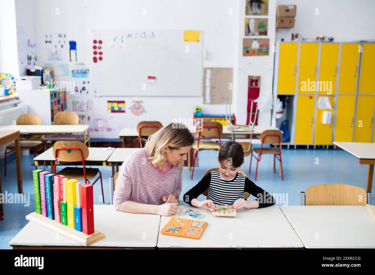 Teacher using geoboard in class, teaching students, explaining geometry ...