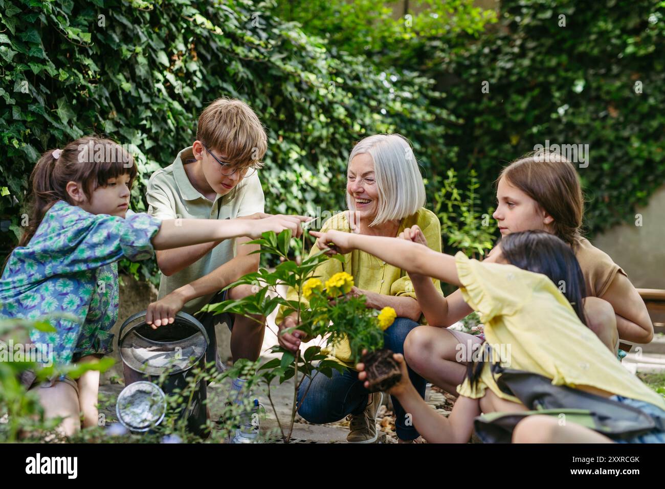 Young kids taking care of plants in school garden during at outdoor ...