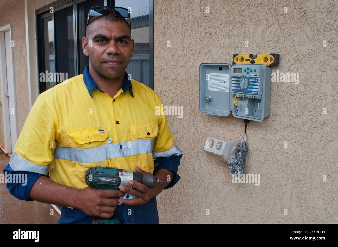 An indigenous trainee electrician installing wiring in newly ...