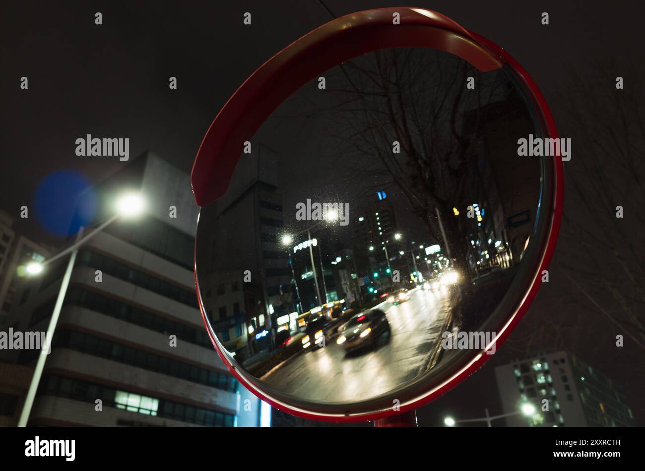 Round street mirror mounted at the crossing of urban roads, close-up ...