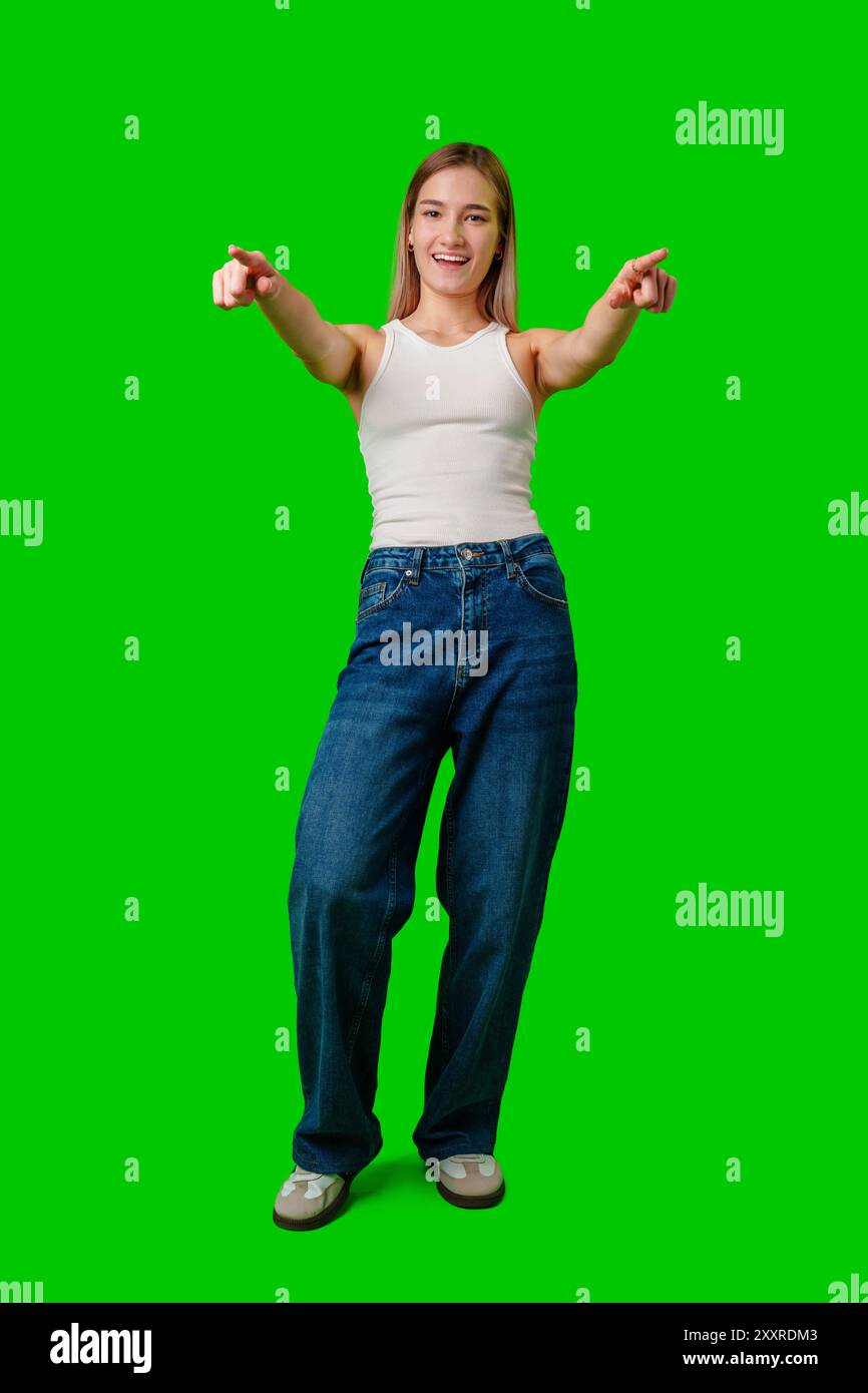 Young Woman Points to Camera While Smiling in Front of Green Screen ...