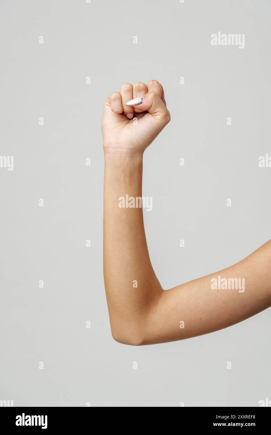 Close Up of Woman's Arm With Fist Raised in Front of a Grey Background ...