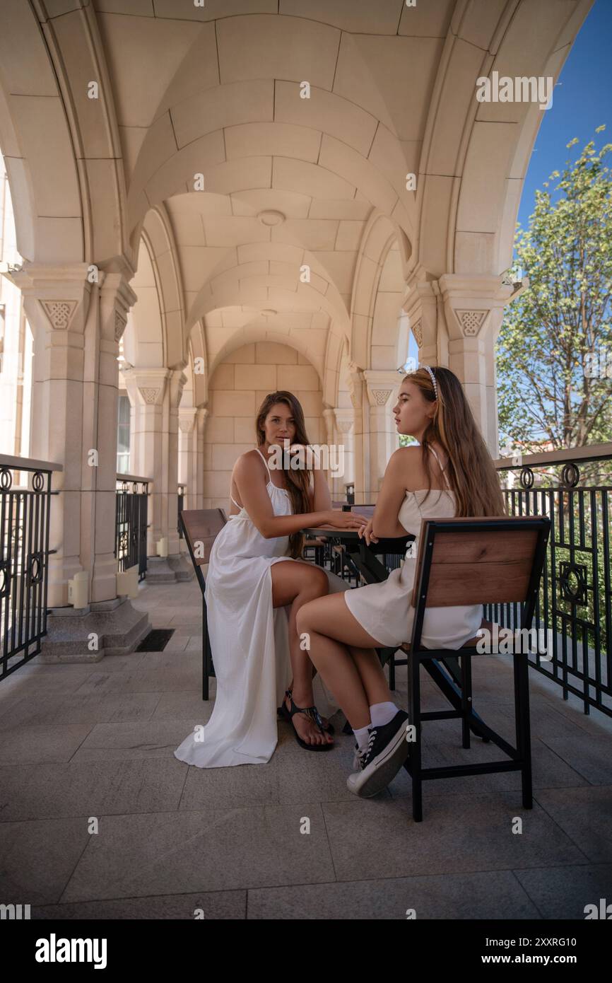 Women, Balcony, Conversation. Two women in white dresses sitting on a ...