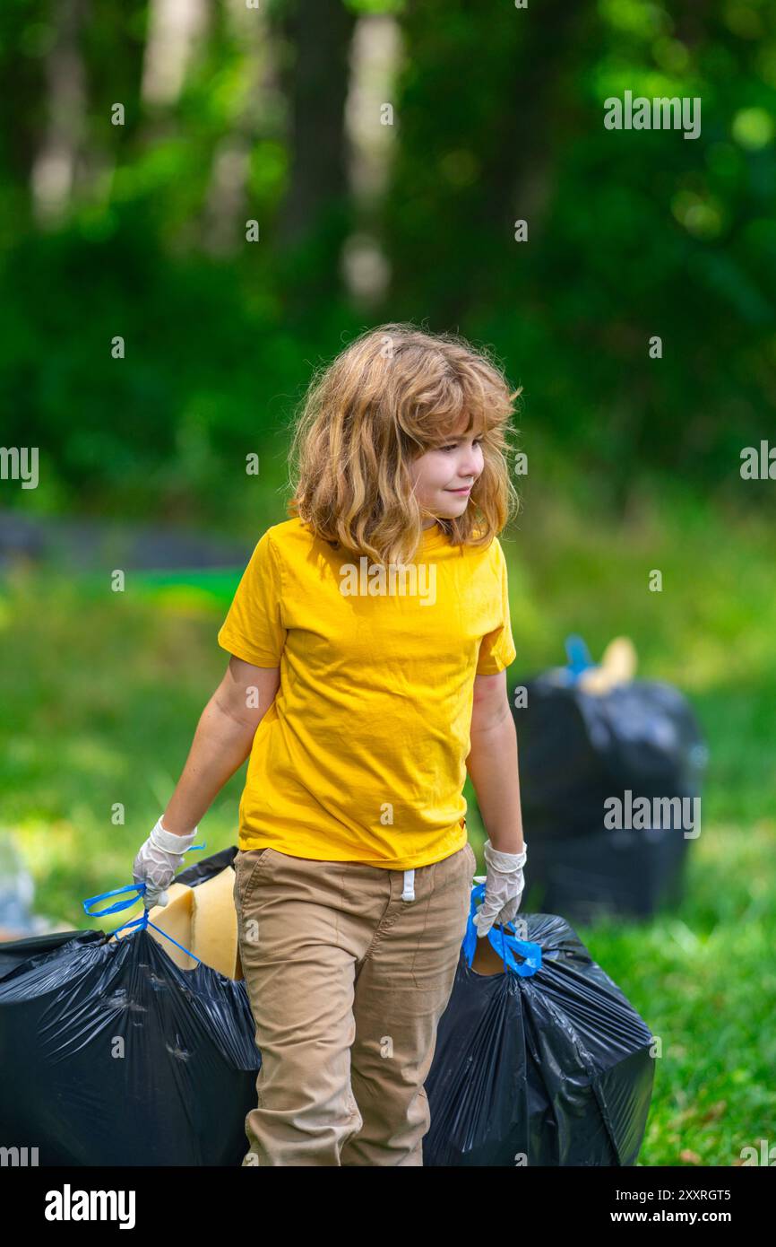 Environment plastic pollution. Volunteer kid collecting trash in the forest and holding a ...
