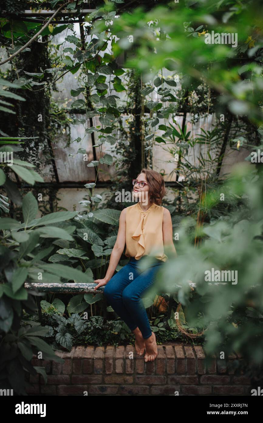 Beautiful woman sitting in botanical garden, in the middle of lush ...