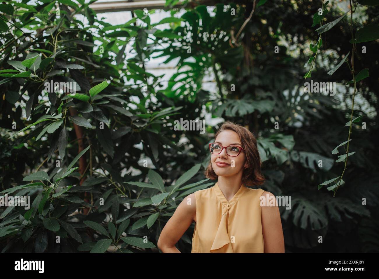 Beautiful woman standing in botanical garden, in the middle of lush ...