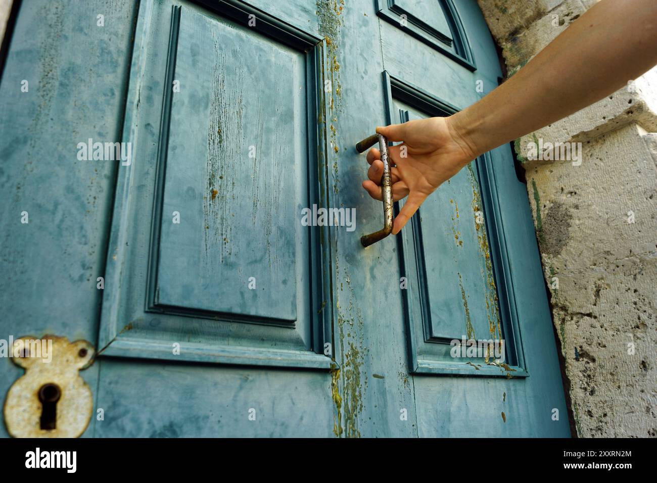 Male hand holding door handle on blue wooden door with unusual keyhole ...