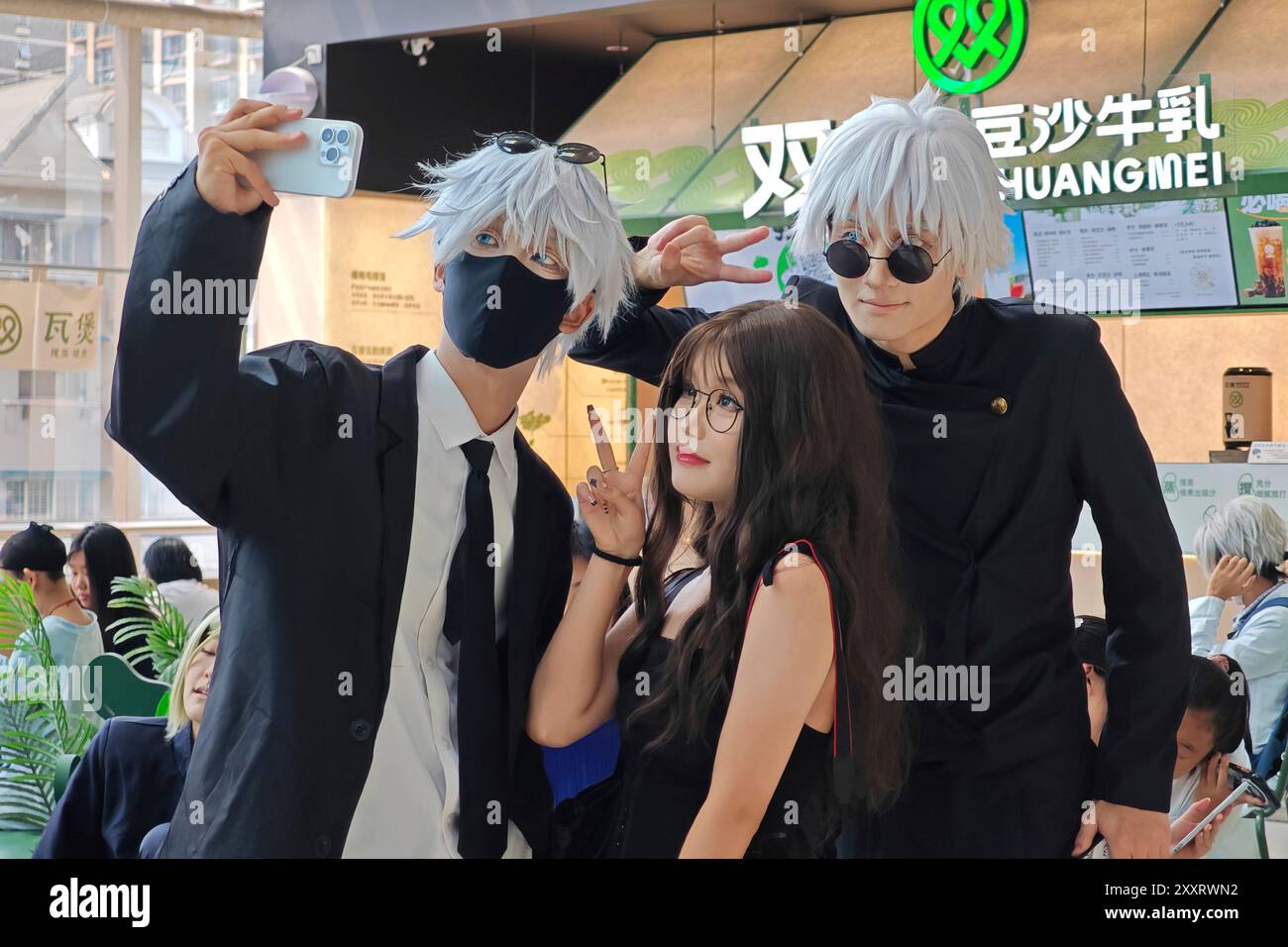 A woman poses for photos with two cosplayers in a shopping mall in ...