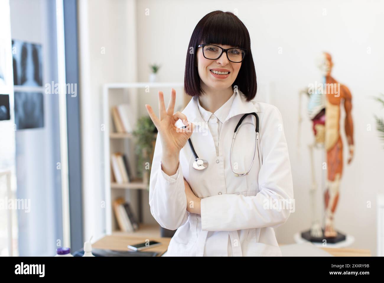 Confident female doctor giving ok sign in medical office Stock Photo ...