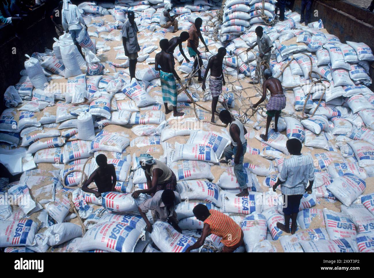 Workers unload sacks of rice from a relief ship in the port of ...
