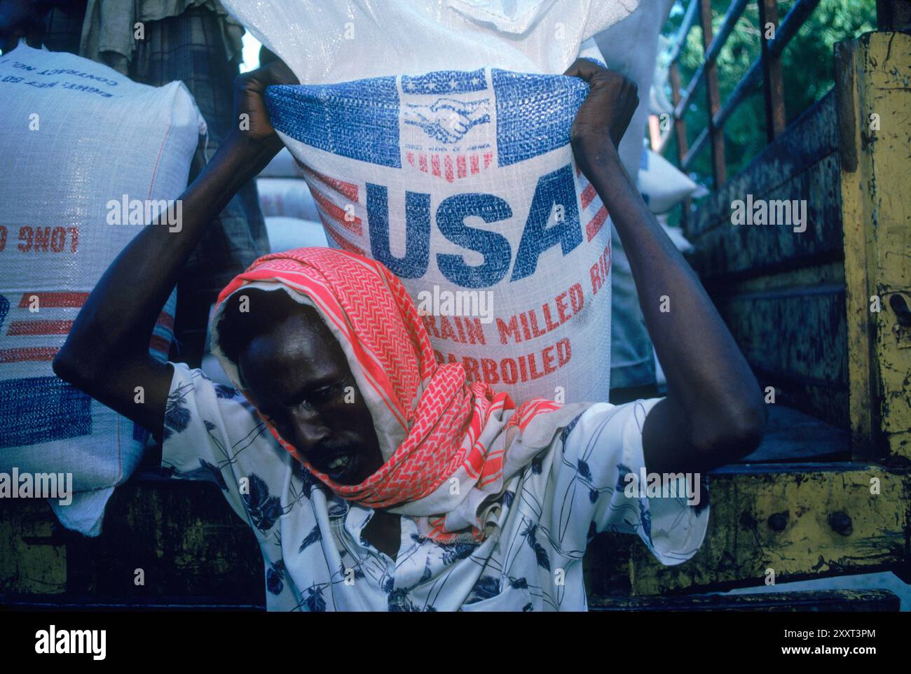 Somali worker carries a sack of rice from a truck to a warehouse ...