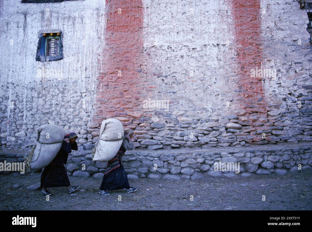 Carrying crops past a brick wall, Lo Manthang, Nepal Stock Photo - Alamy