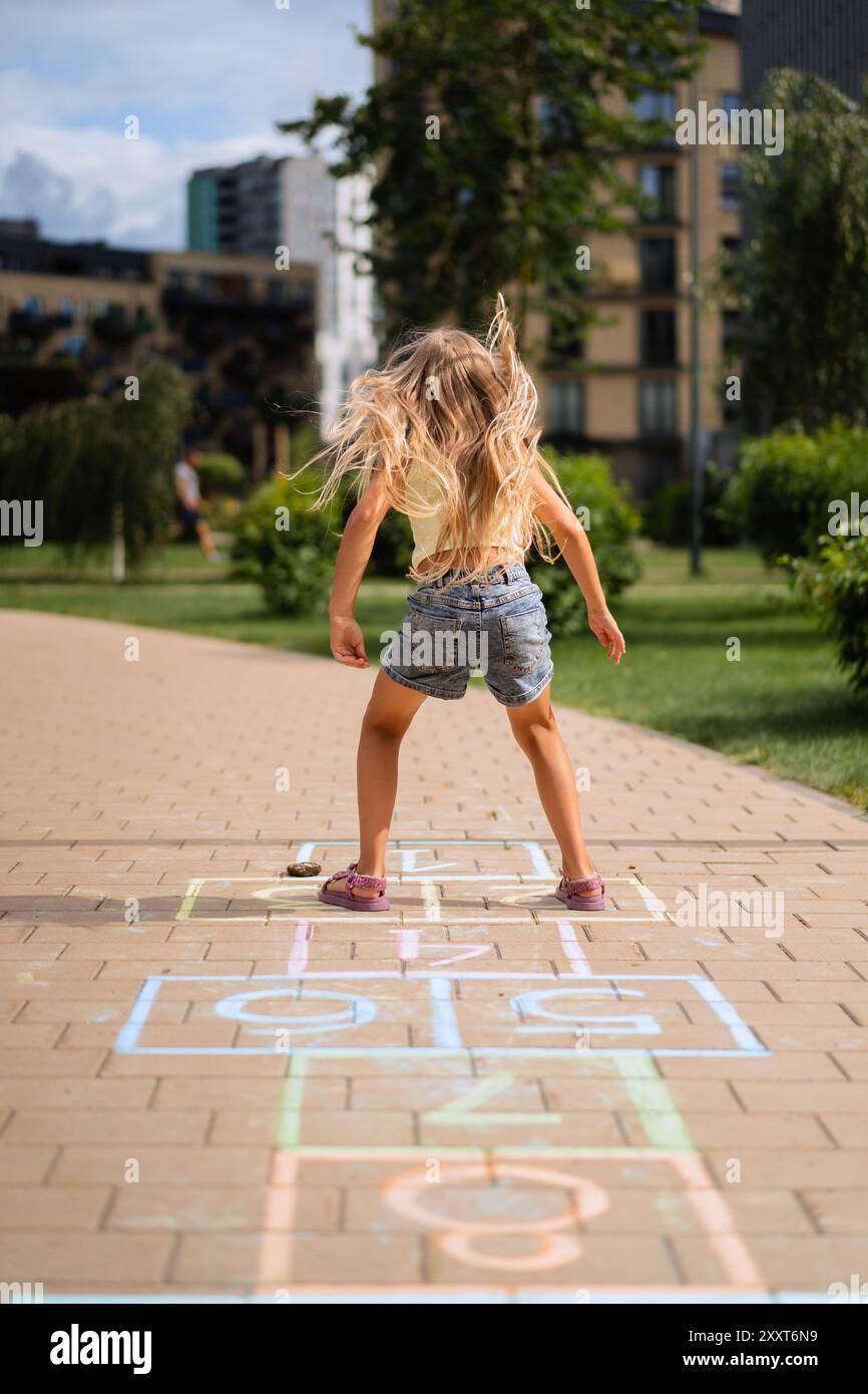 Full length of girl playing hopscotch Stock Photo - Alamy