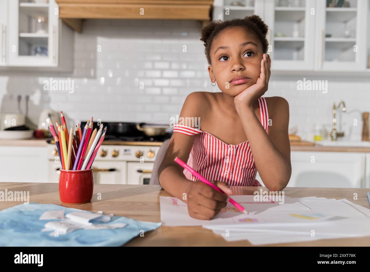 Pondering African American kid girl drawing in kitchen Stock Photo - Alamy
