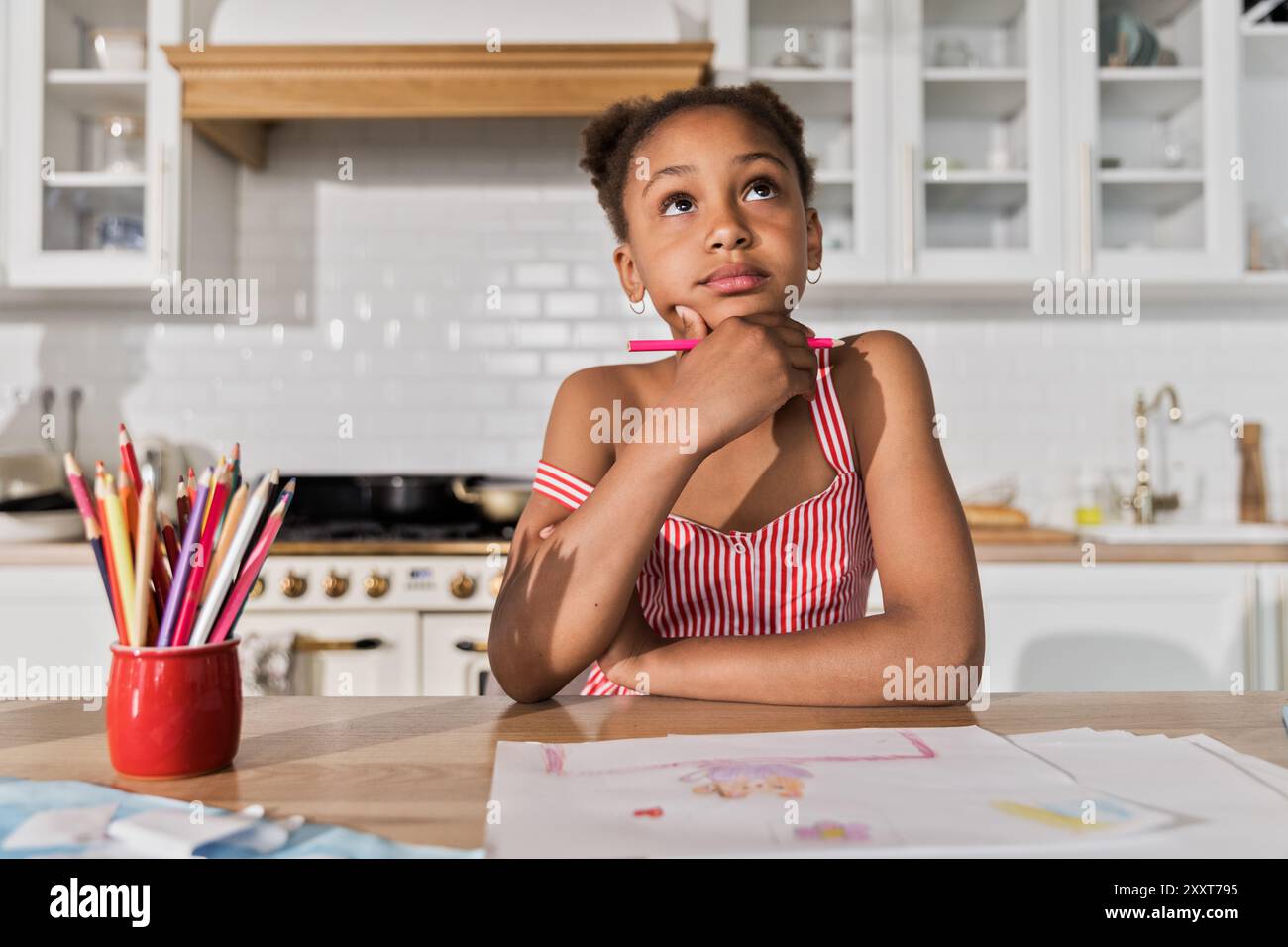 Pondering African American kid girl drawing in kitchen Stock Photo - Alamy
