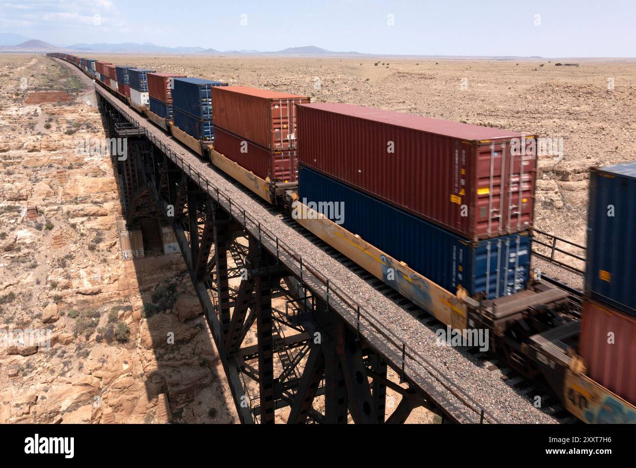 A container stack freight train passing over a desert bridge Stock ...