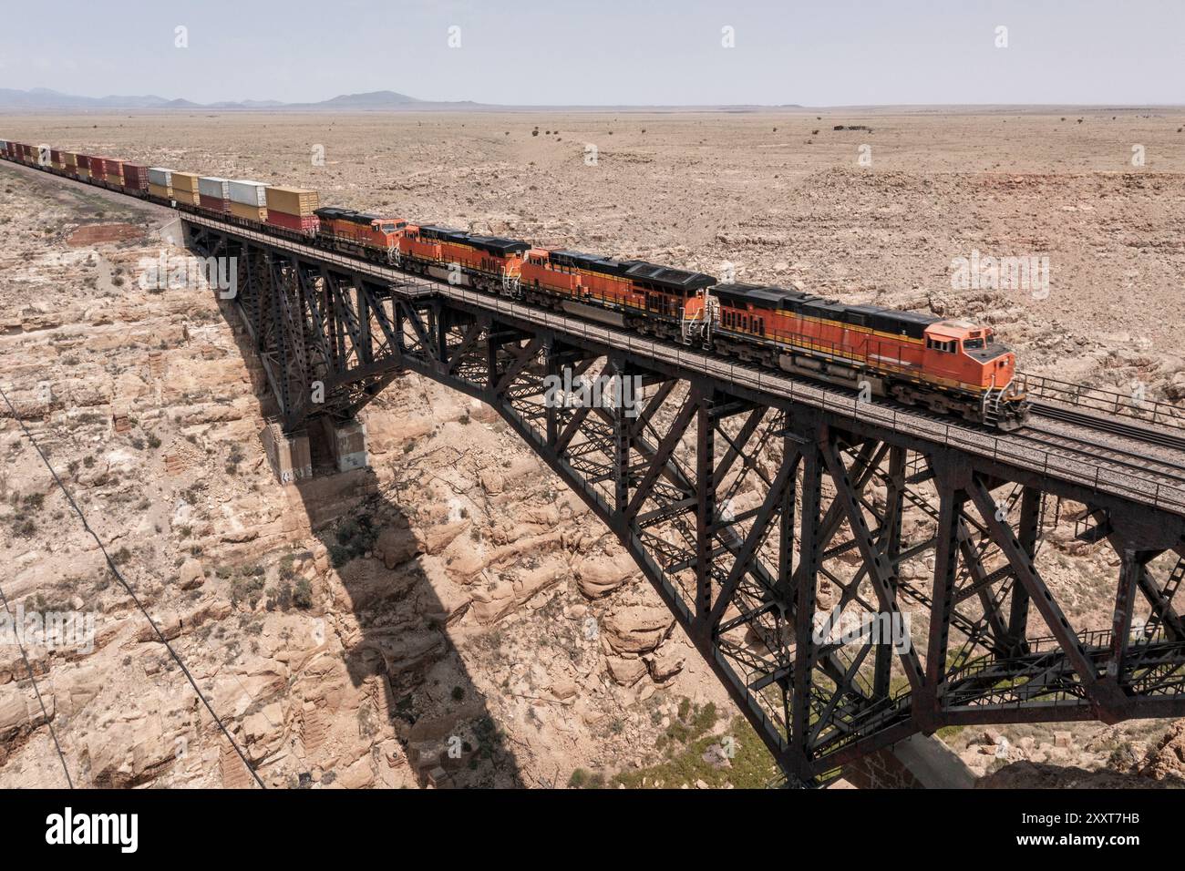 A modern freight train passes over a desert train bridge Stock Photo ...