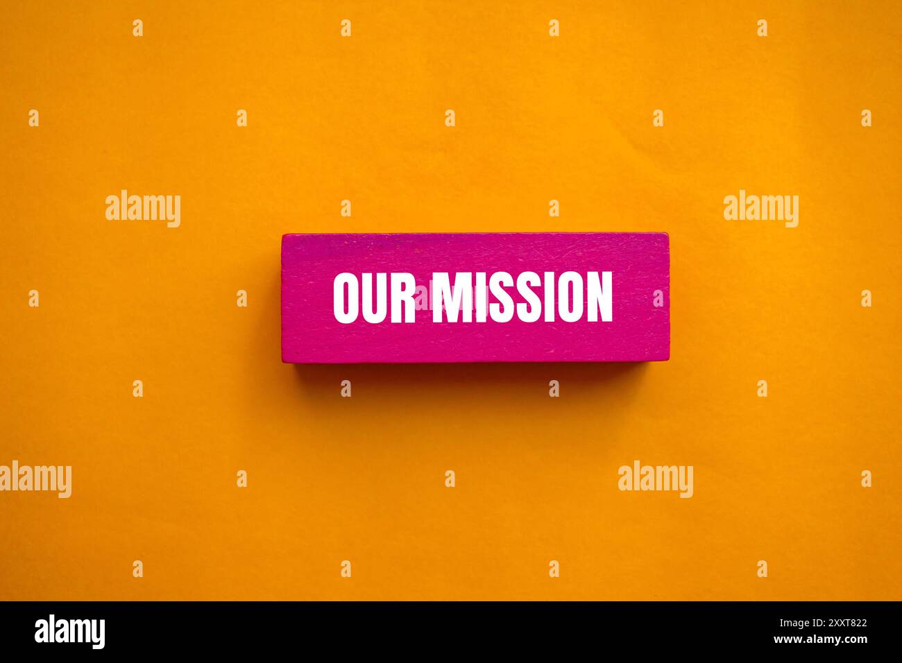 Our mission message written on pink wooden block with orange background ...
