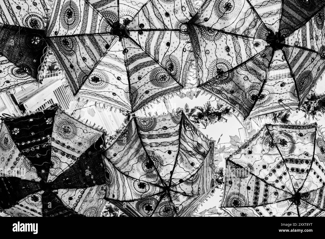 Patterns of umbrellas hung upside down as shade over cafe tables ...