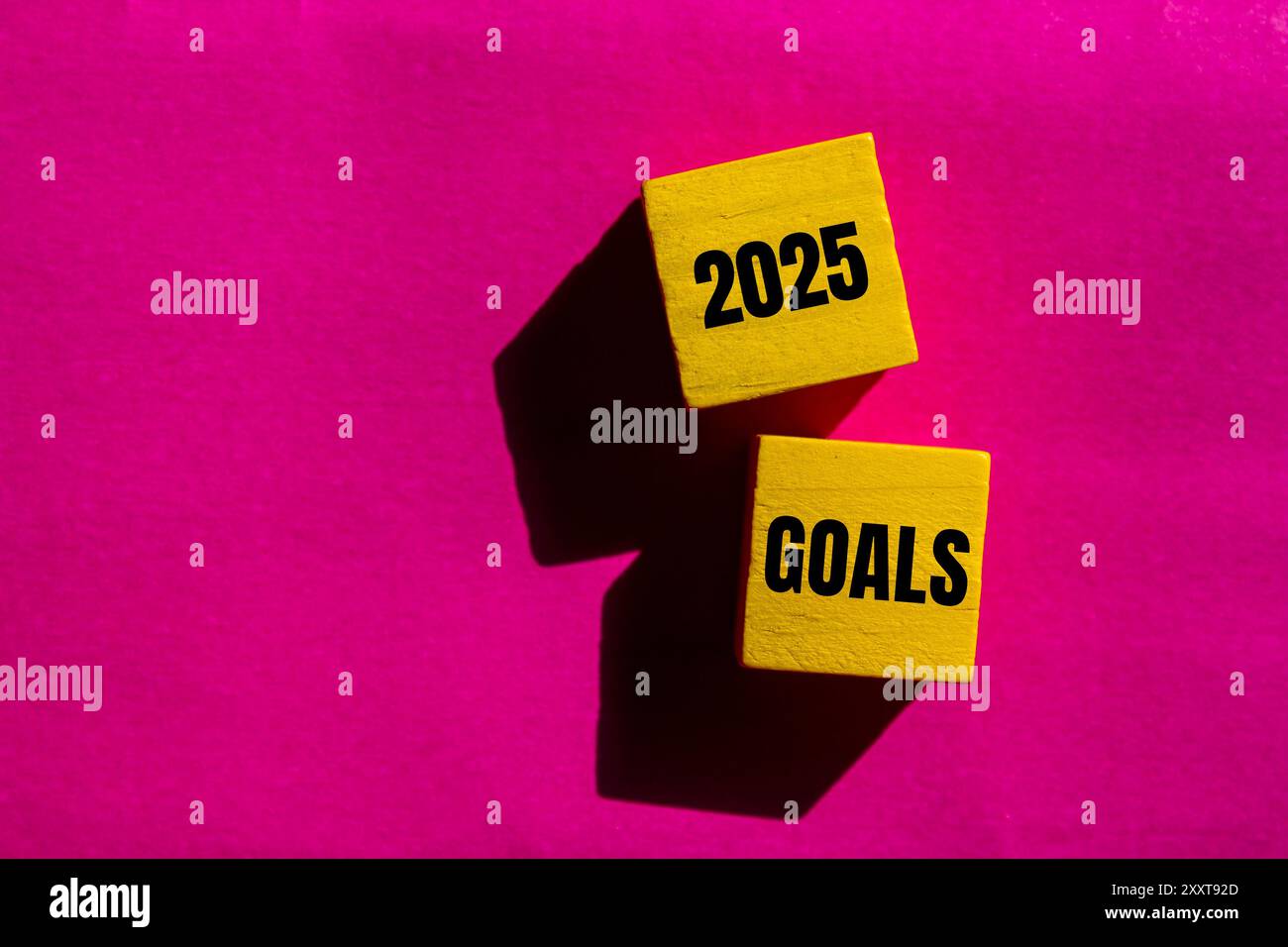 2025 goals message written on yellow wooden cubes with pink background ...