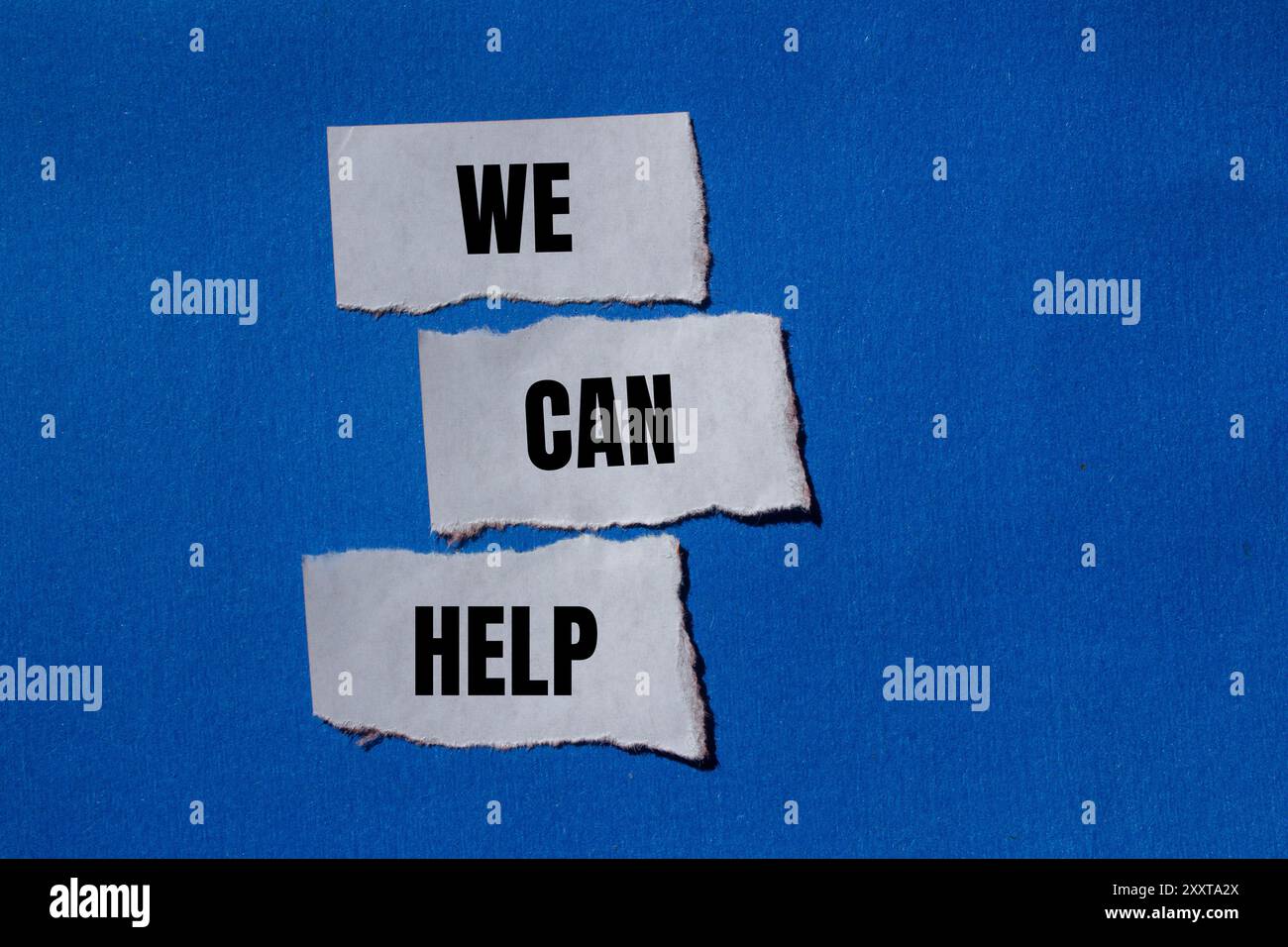 We can help message written on ripped paper pieces with blue background ...