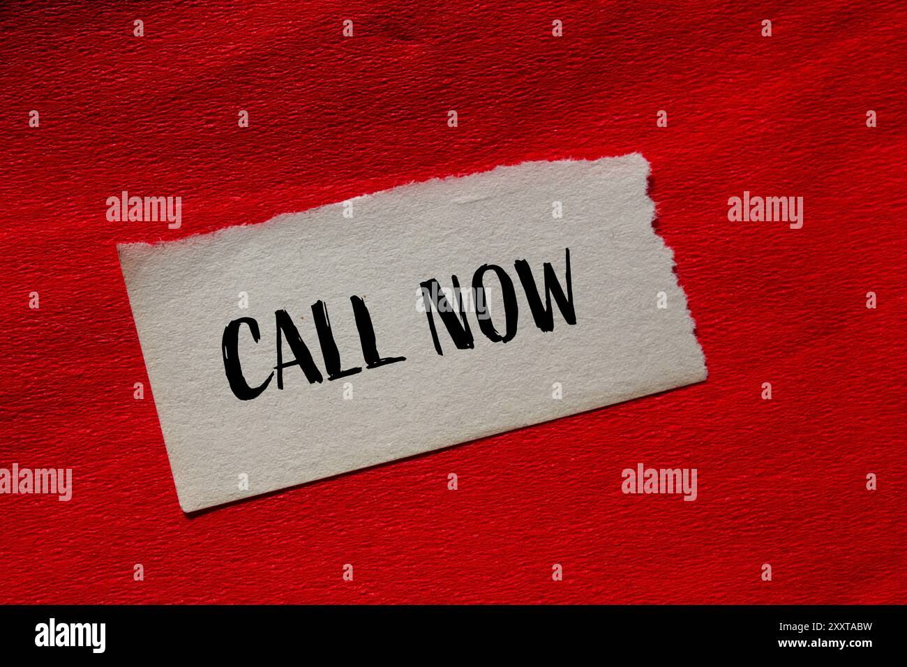 Call now message written on ripped torn paper piece on red background ...