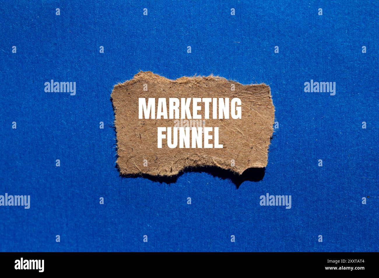 Marketing funnel message written on ripped torn cardboard paper piece on blue background ...