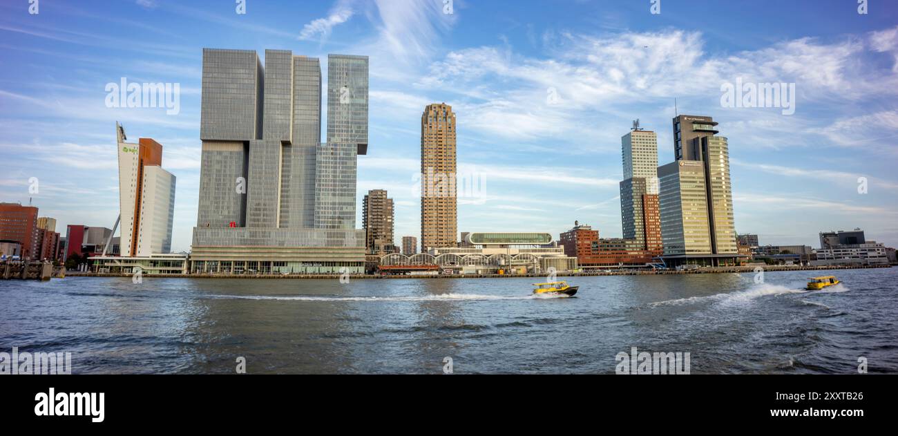 Wave creating water taxi passing urban skyline with Erasmus bridge and ...