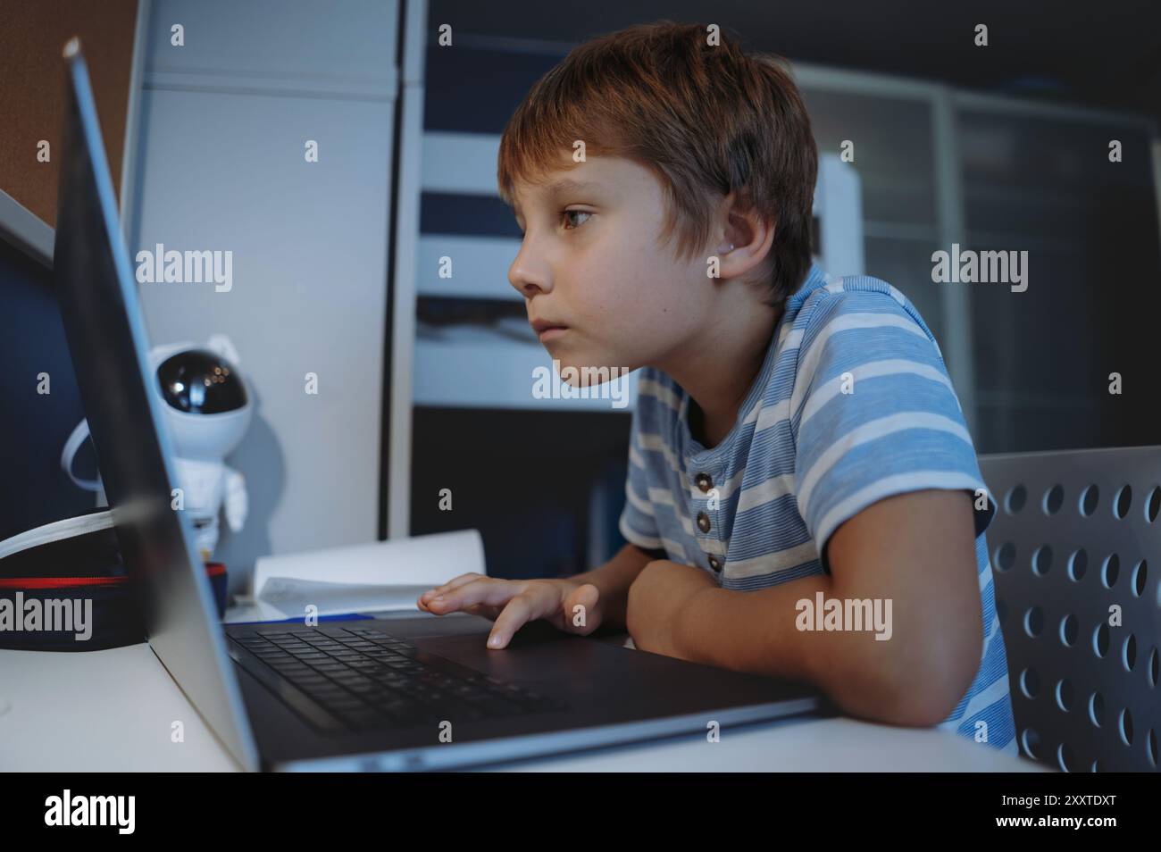 caucasian little boy studying at home typing on laptop. Distant ...