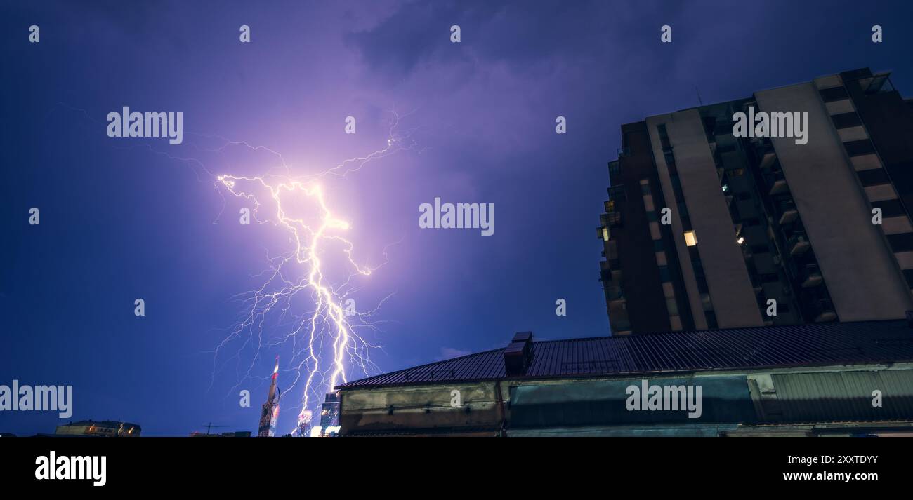 Lightning illuminating urban skyline at night during thunderstorm, with ...