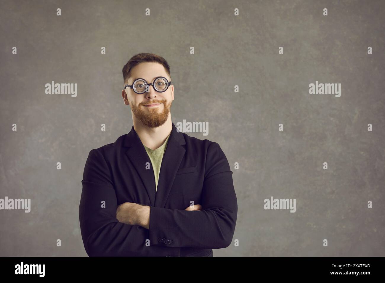 Portrait of a funny nerd in glasses standing arms folded on a copy ...