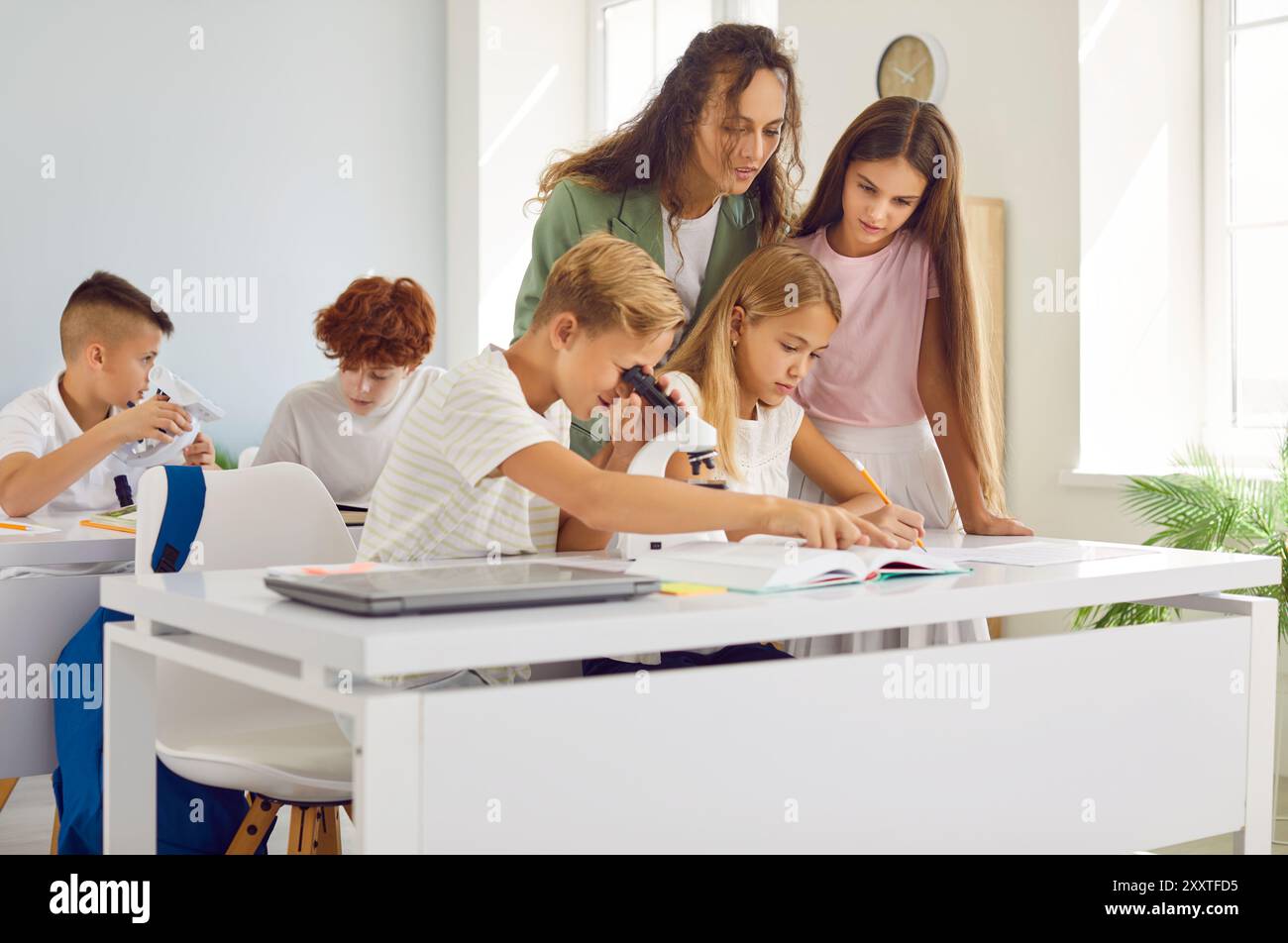 Teacher Assisting Students In Classroom During Lesson Stock Photo - Alamy