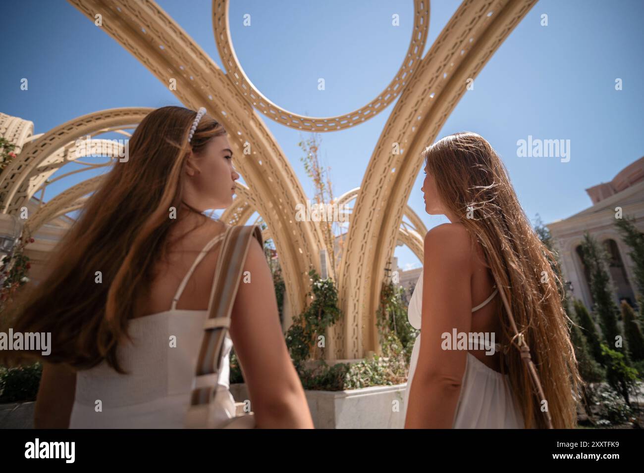 Women, Golden Arches, Dubai - Two women stand facing a golden arch ...